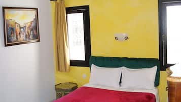 Um quarto com uma cama, um quadro, uma janela com cortinas e uma luminária no teto.