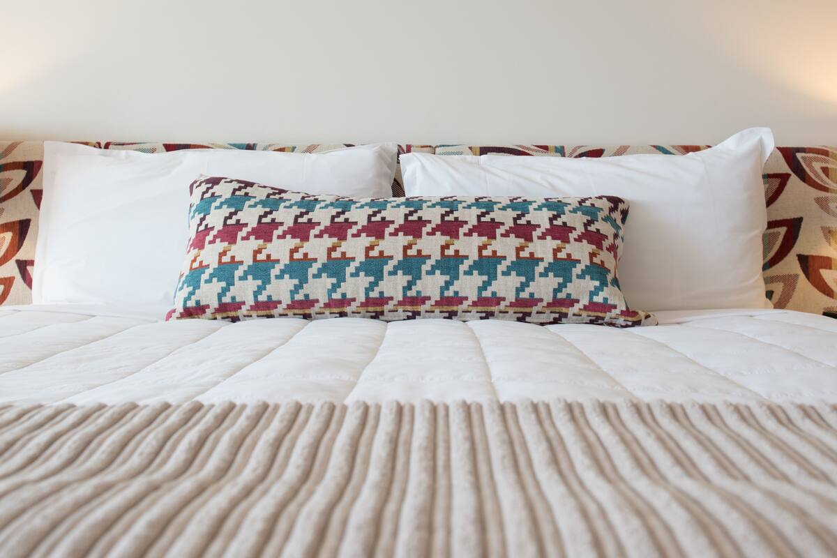 Uma cama com uma almofada estampada e uma almofada branca lisa.