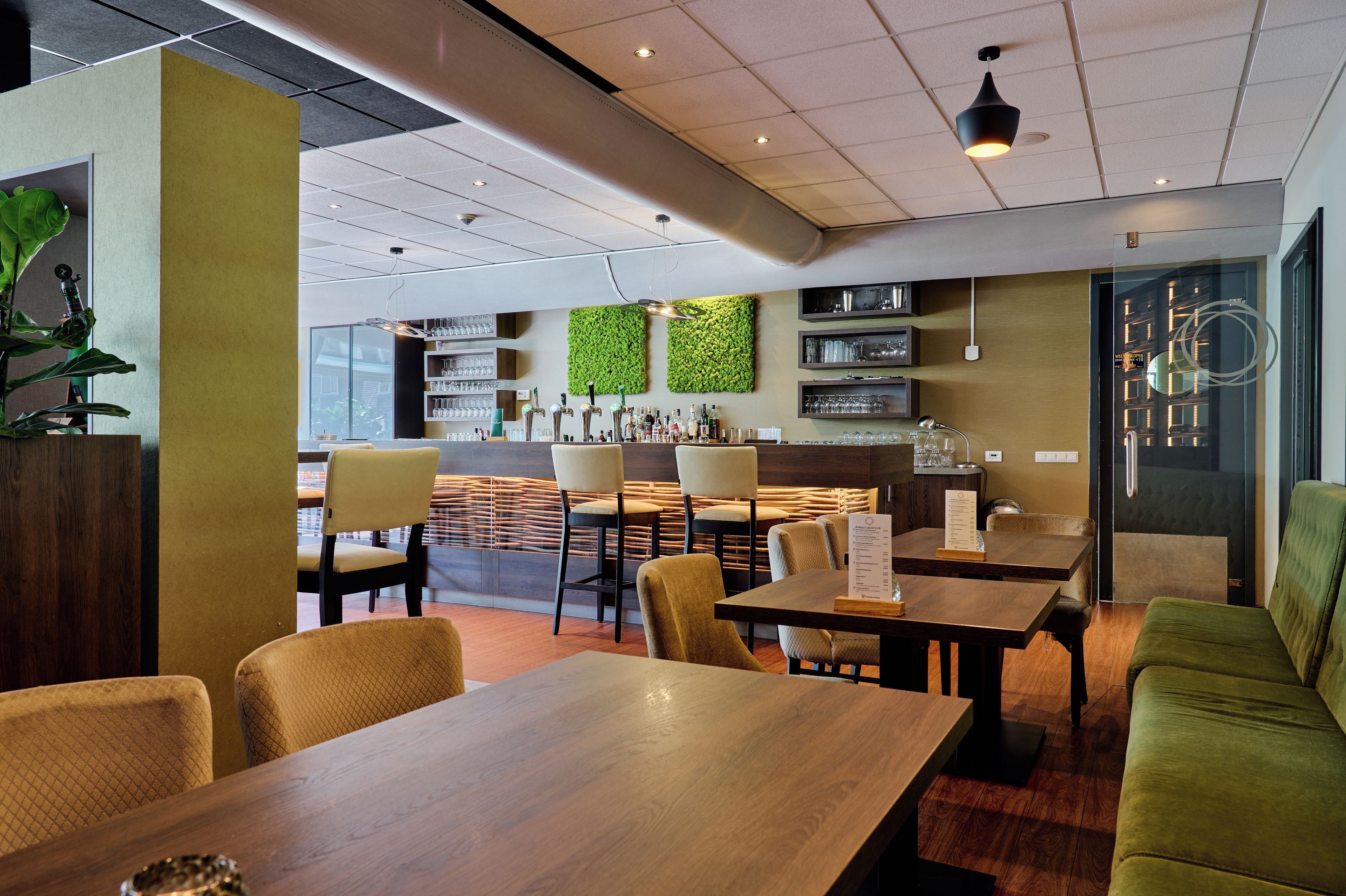Uma área de bar moderna com parede verde, assentos e suporte para cardápio.