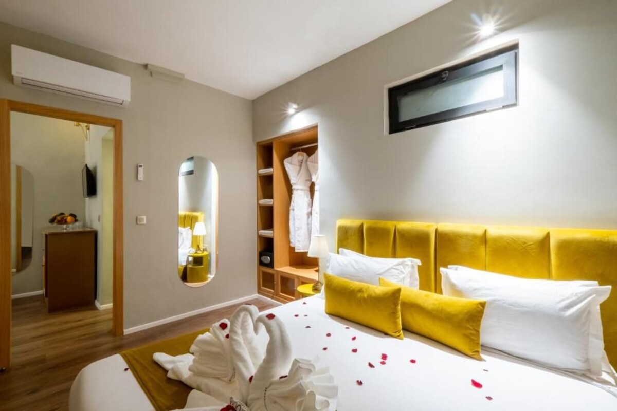 Quarto de hotel com cama, guarda-roupa, espelho e televisão.