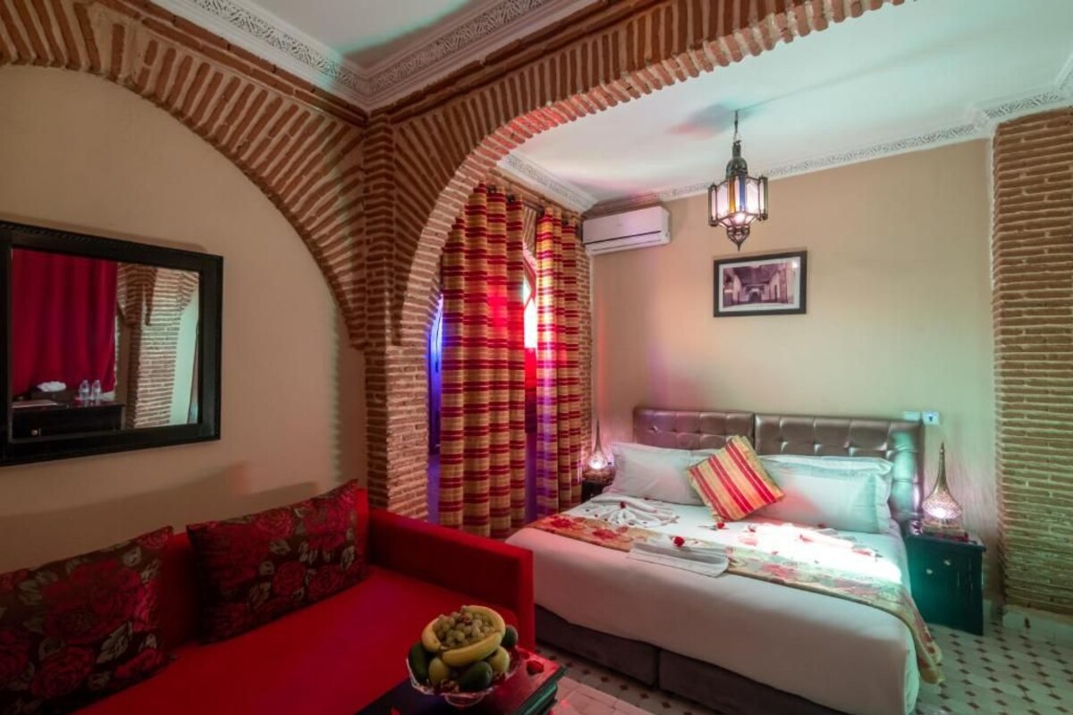 Quarto de hotel com cama, sofá e um arco decorativo.