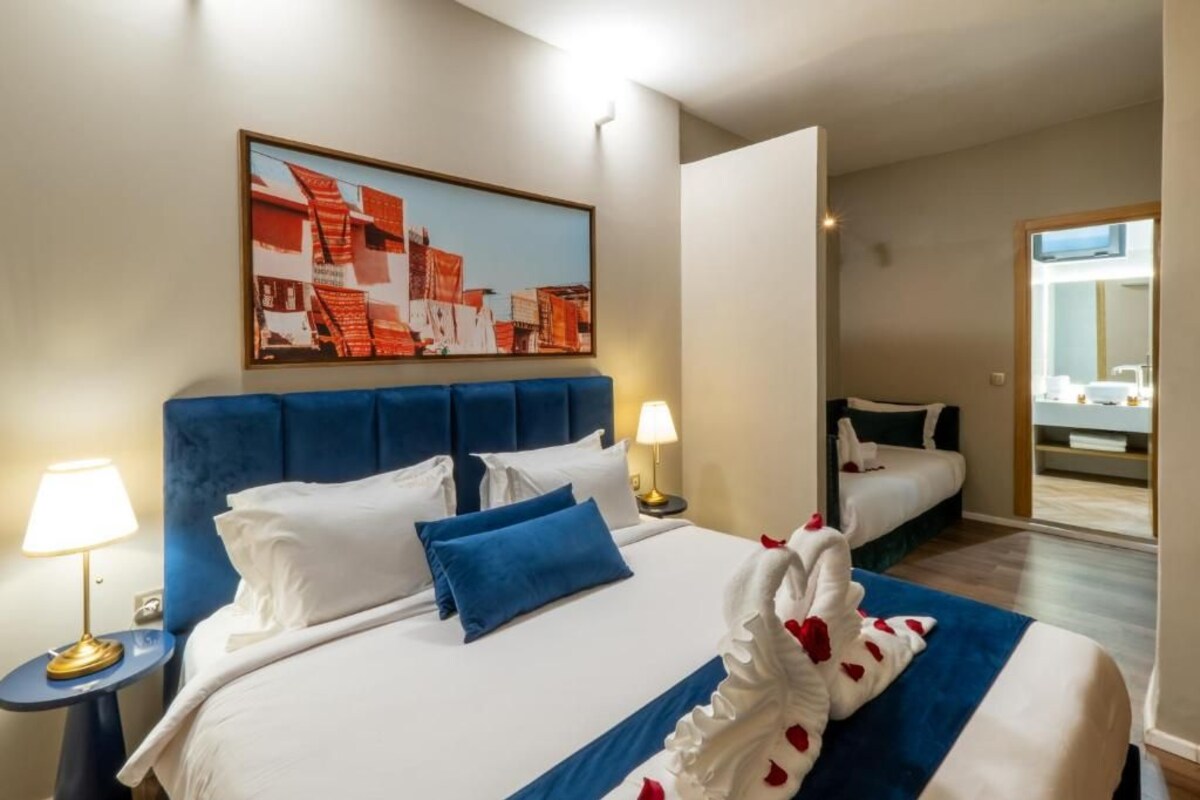 Quarto de hotel com uma cama grande, uma cama menor, um quadro na parede e um espelho no canto.