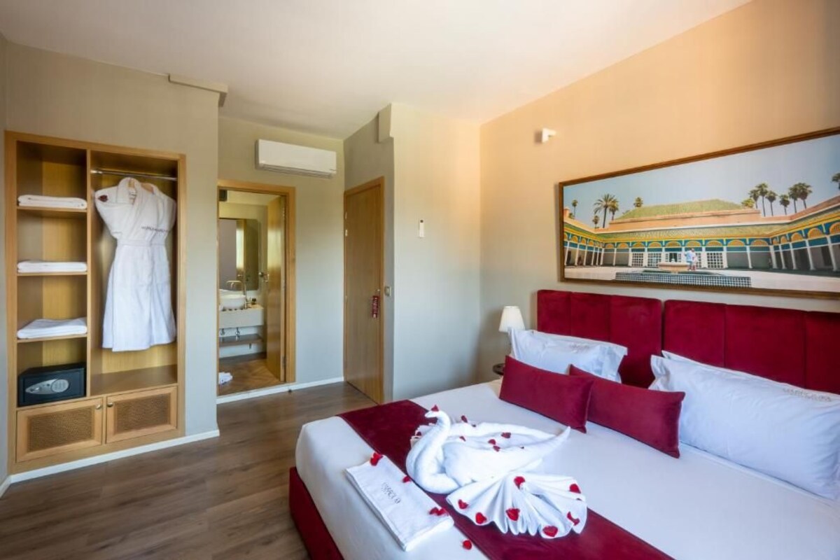 Quarto de hotel com uma cama, um armário para roupões e uma pintura de um edifício.