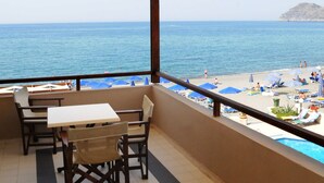 Uma varanda com vista para o mar, uma piscina e guarda-sóis de praia.