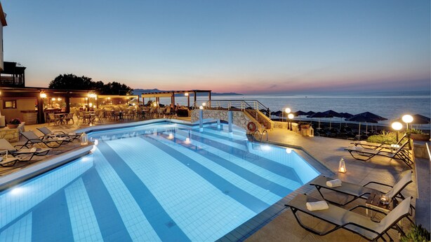 Piscina no terraço com espreguiçadeiras e guarda-sóis, com vista para o mar.