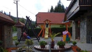 Um parquinho infantil com balanços e escorregadores, cercado por um jardim com uma placa 'Gorajurist'.