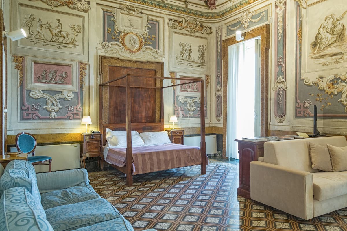 Um quarto luxuoso com uma cama de dossel, um sofá e decorações de parede ornamentadas.