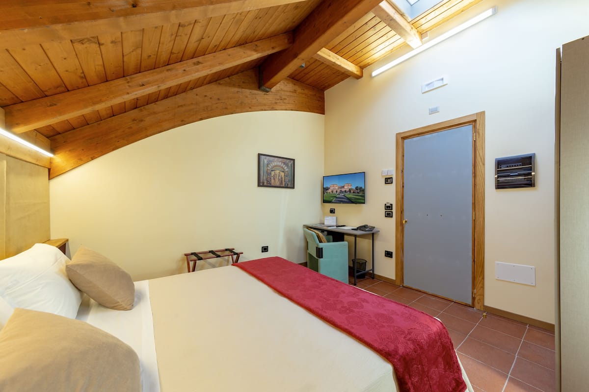 Quarto com uma cama, uma escrivaninha e uma porta.
