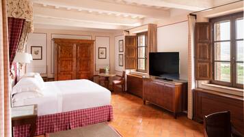 Quarto de hotel com cama, escrivaninha, televisão e janela com vista.