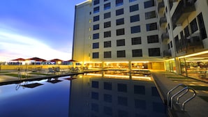 Um hotel moderno com piscina, área de estar externa e fachada bem iluminada.