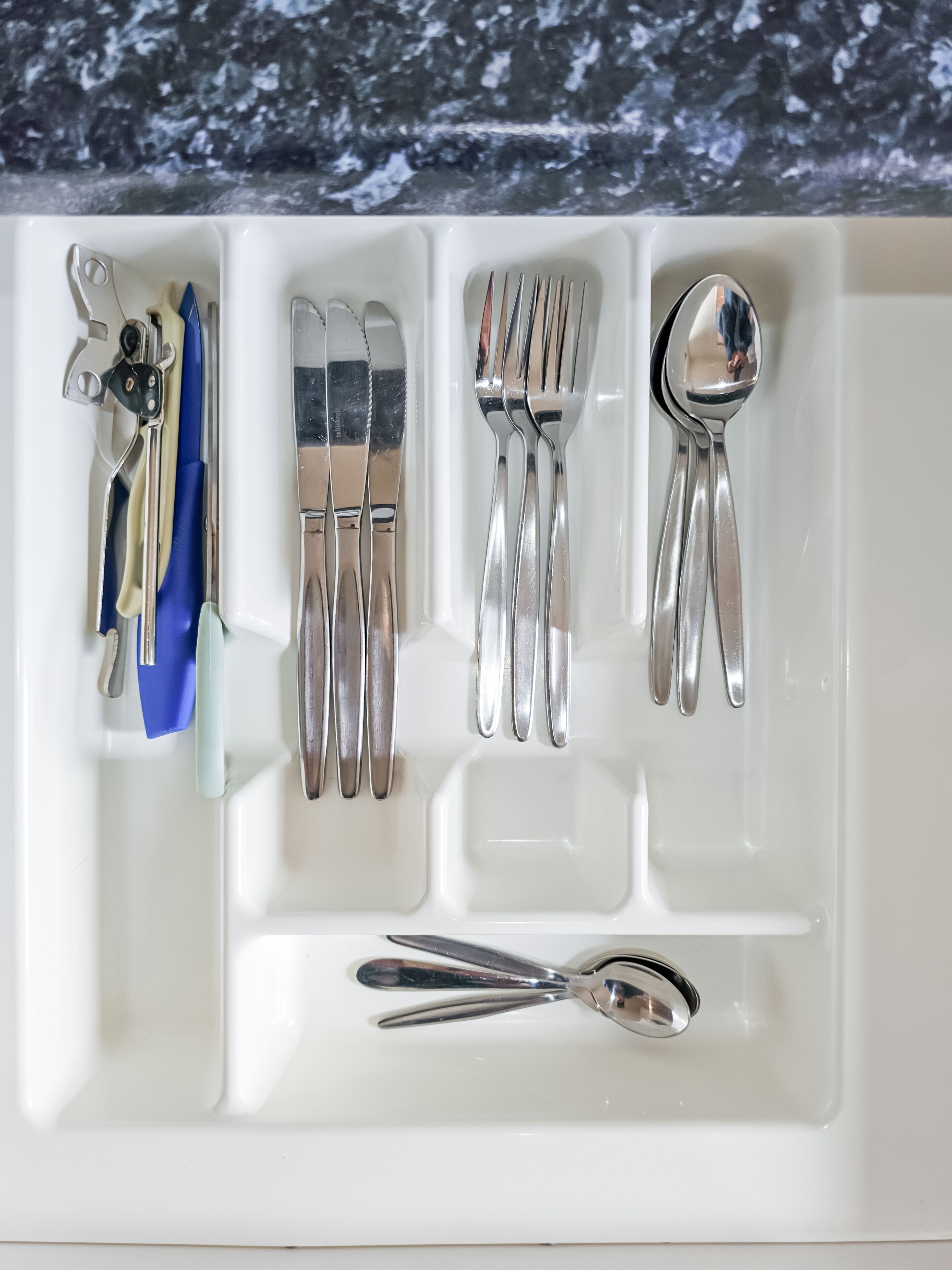 Organizador de gaveta com utensílios e uma colher.