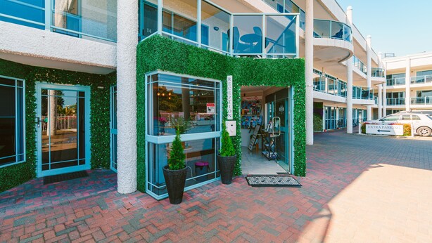 Um edifício moderno com entrada de vidro, balcão de recepção e placa indicando estacionamento adicional.