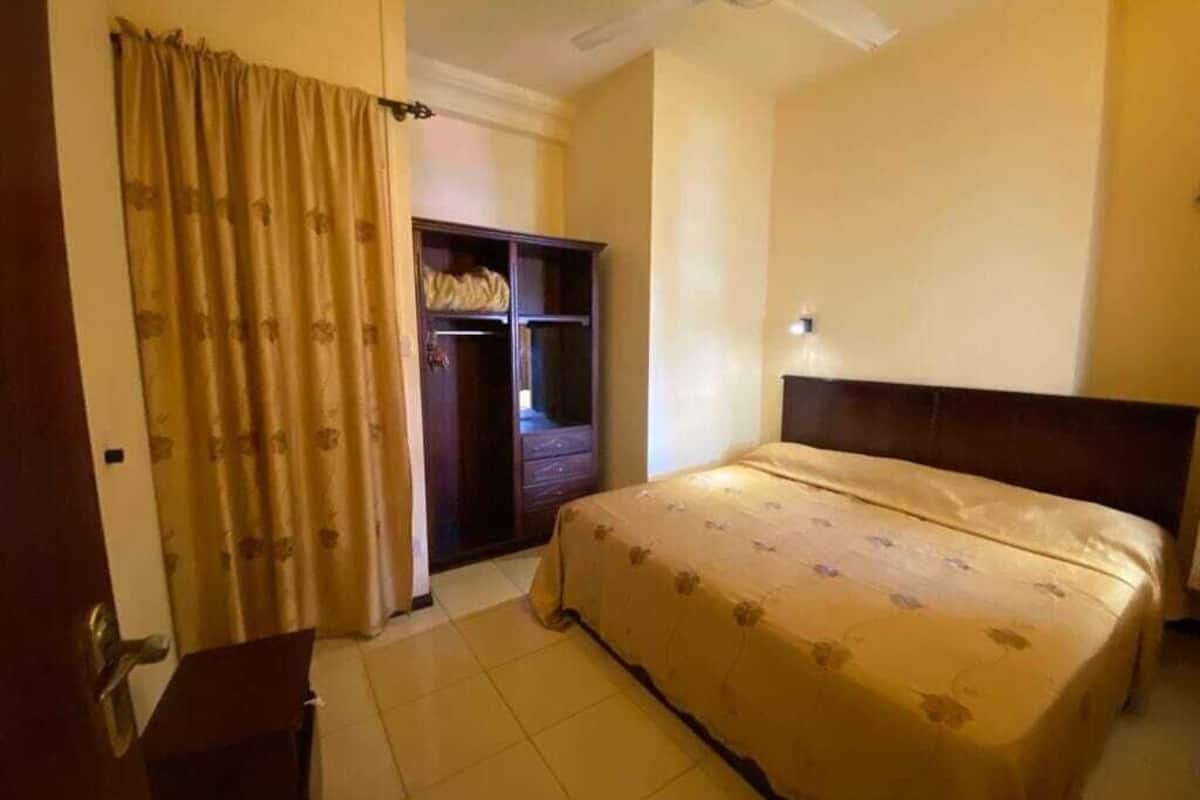 Quarto com uma cama, guarda-roupa e uma porta com cortinas.