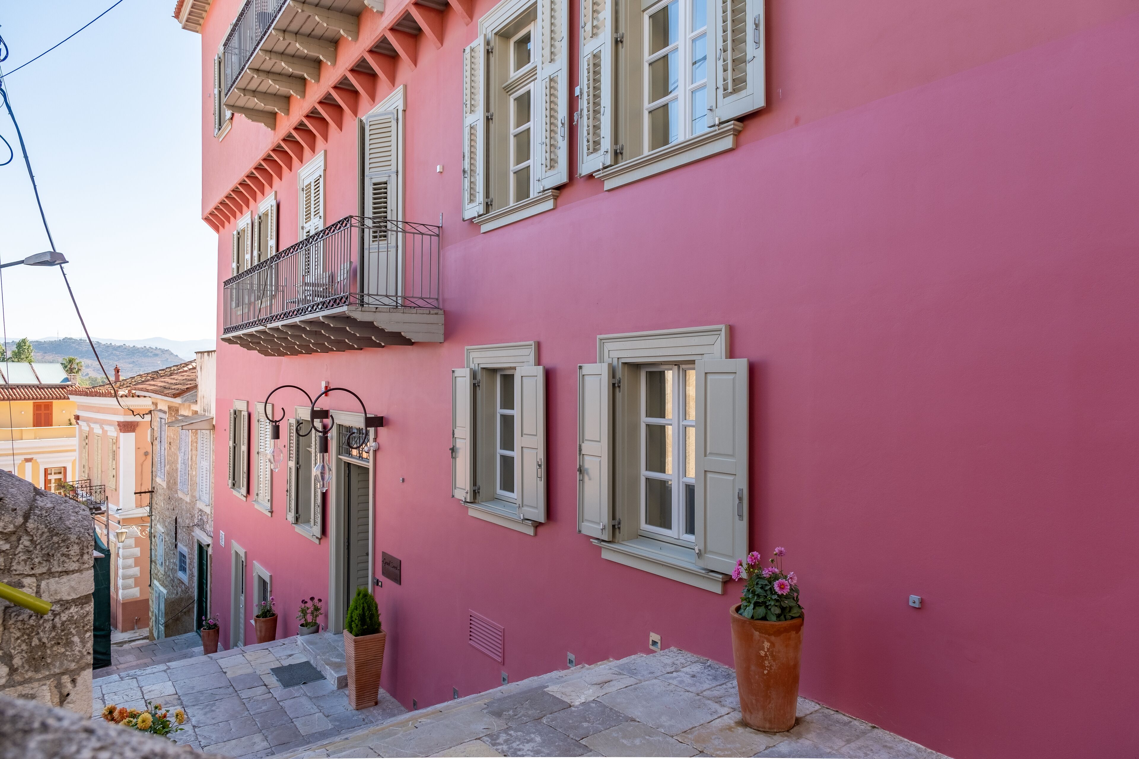 Um edifício rosa com várias janelas e uma varanda.