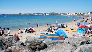 Uma praia com pessoas, tendas e barcos.