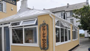 Um edifício chamado 'The Driftwood', com fachada amarela, janelas brancas e uma extensão de vidro.