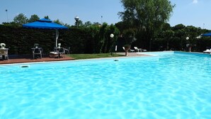 Piscina límpida com água azul, rodeada por espreguiçadeiras e guarda-sóis.