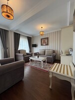 Uma sala de estar com sofá, poltronas, mesa de centro e televisão.