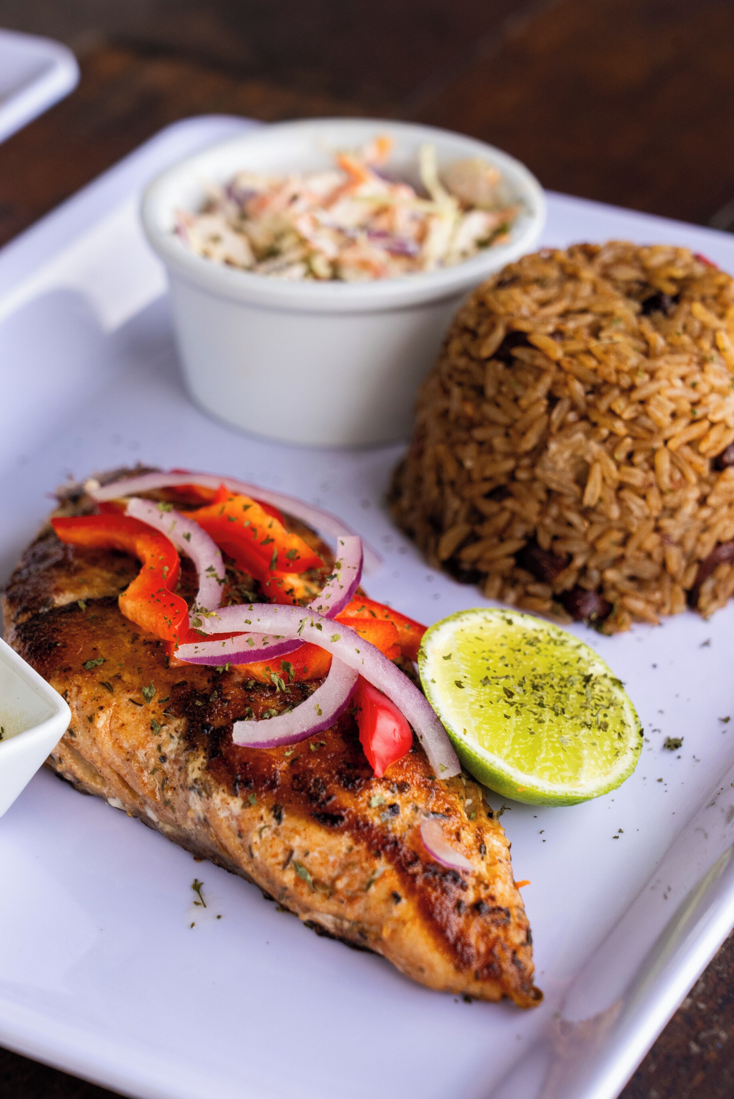 Um prato com frango grelhado, arroz e salada de repolho.