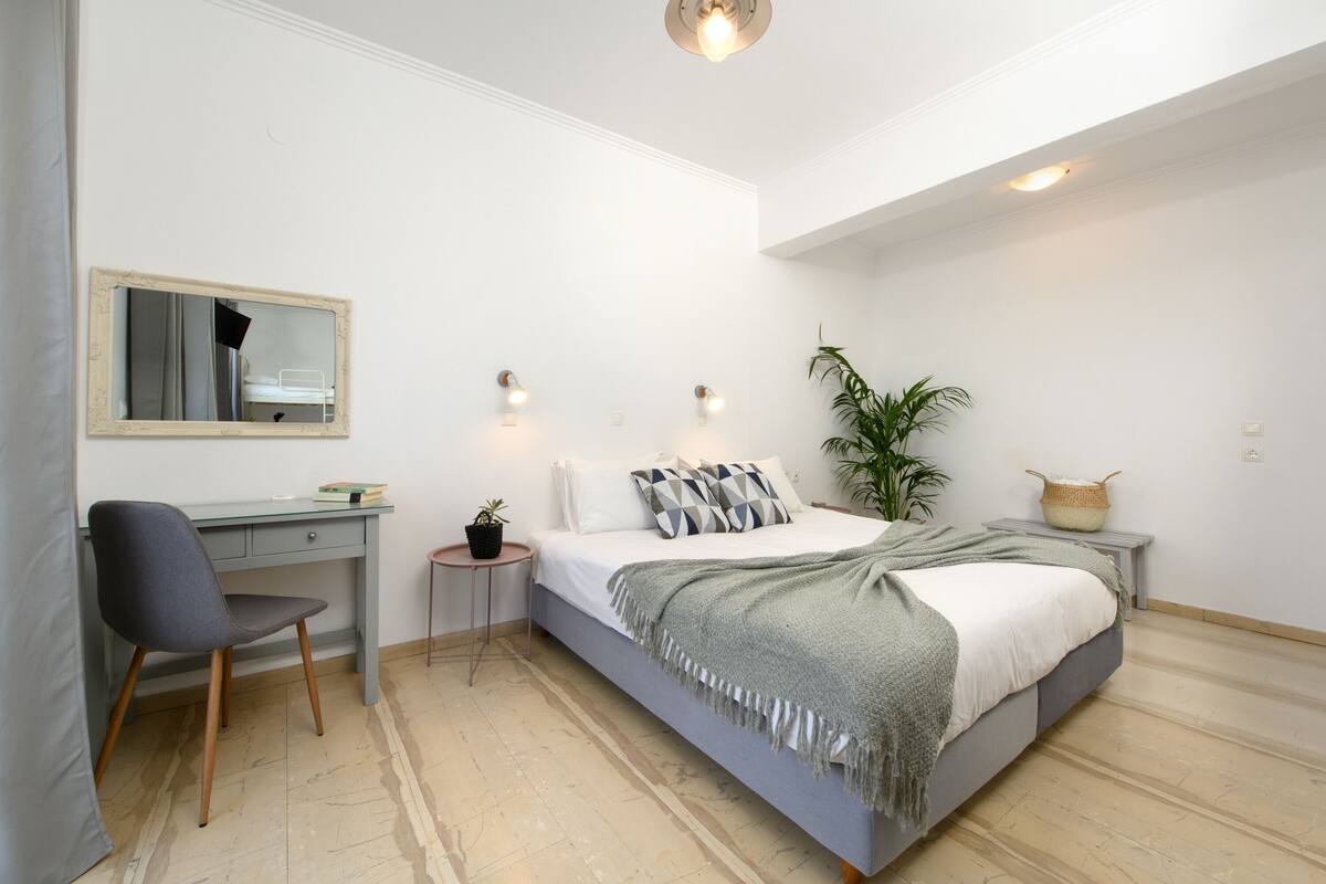 Quarto com cama, escrivaninha, cadeira e espelho.