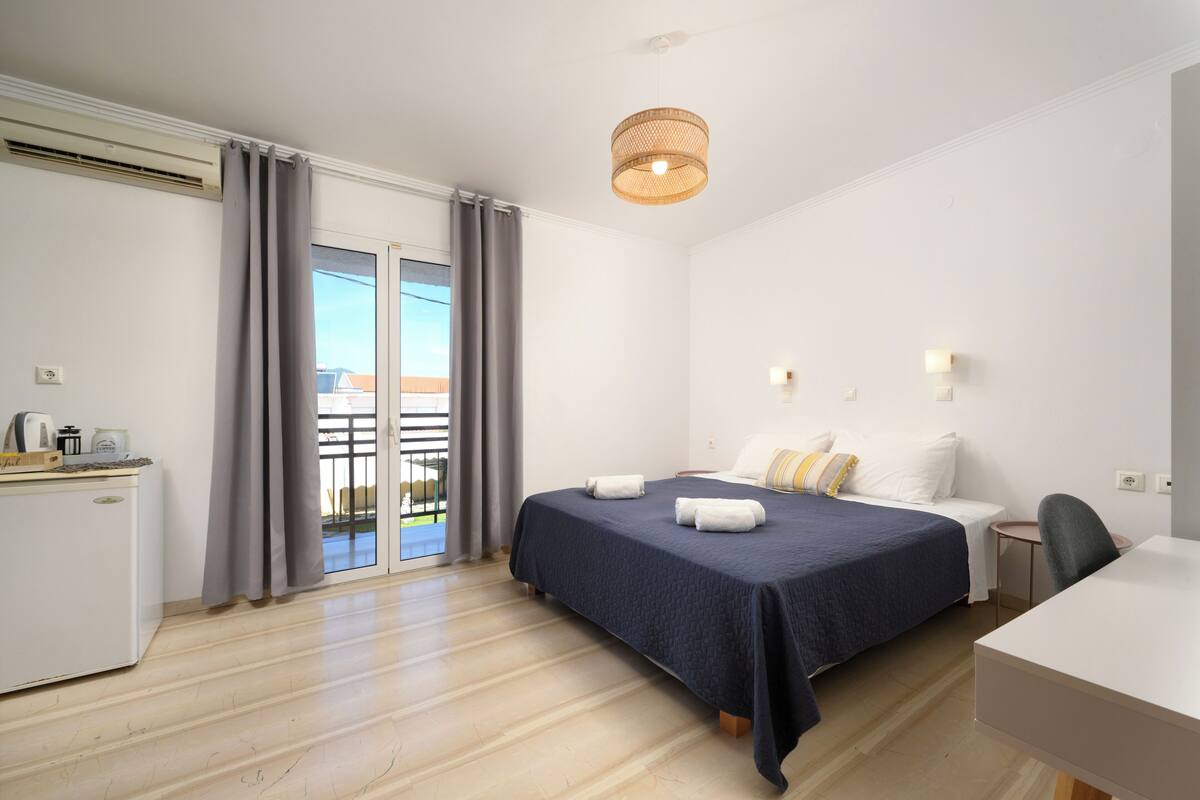 Quarto de hotel com cama, mesa de cabeceira, abajur e vista para o exterior.