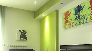 Quarto de hotel com uma cama grande, uma parede de destaque verde e uma pintura na parede.