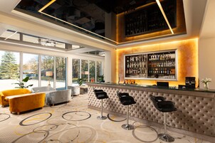 Uma área de bar moderna com balcão, vários bancos e uma grande janela com vista para o exterior.