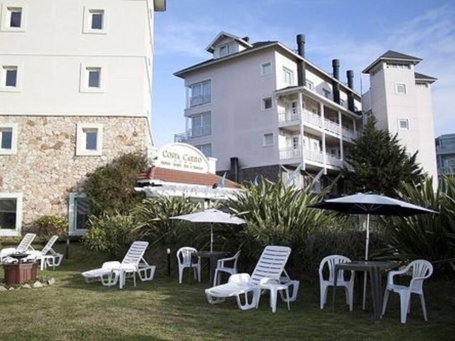 Um hotel com área externa para sentar, fachada de pedra e placa com o nome Costa Carlo.