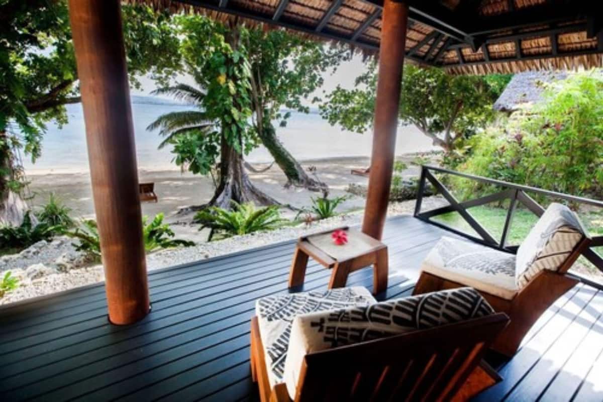 Um deck de madeira com vista para a praia e palmeiras.