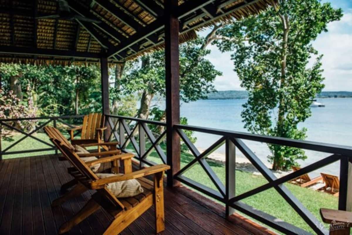 Um deck de madeira com cadeiras de lounge com vista para um corpo d'água e uma costa distante.