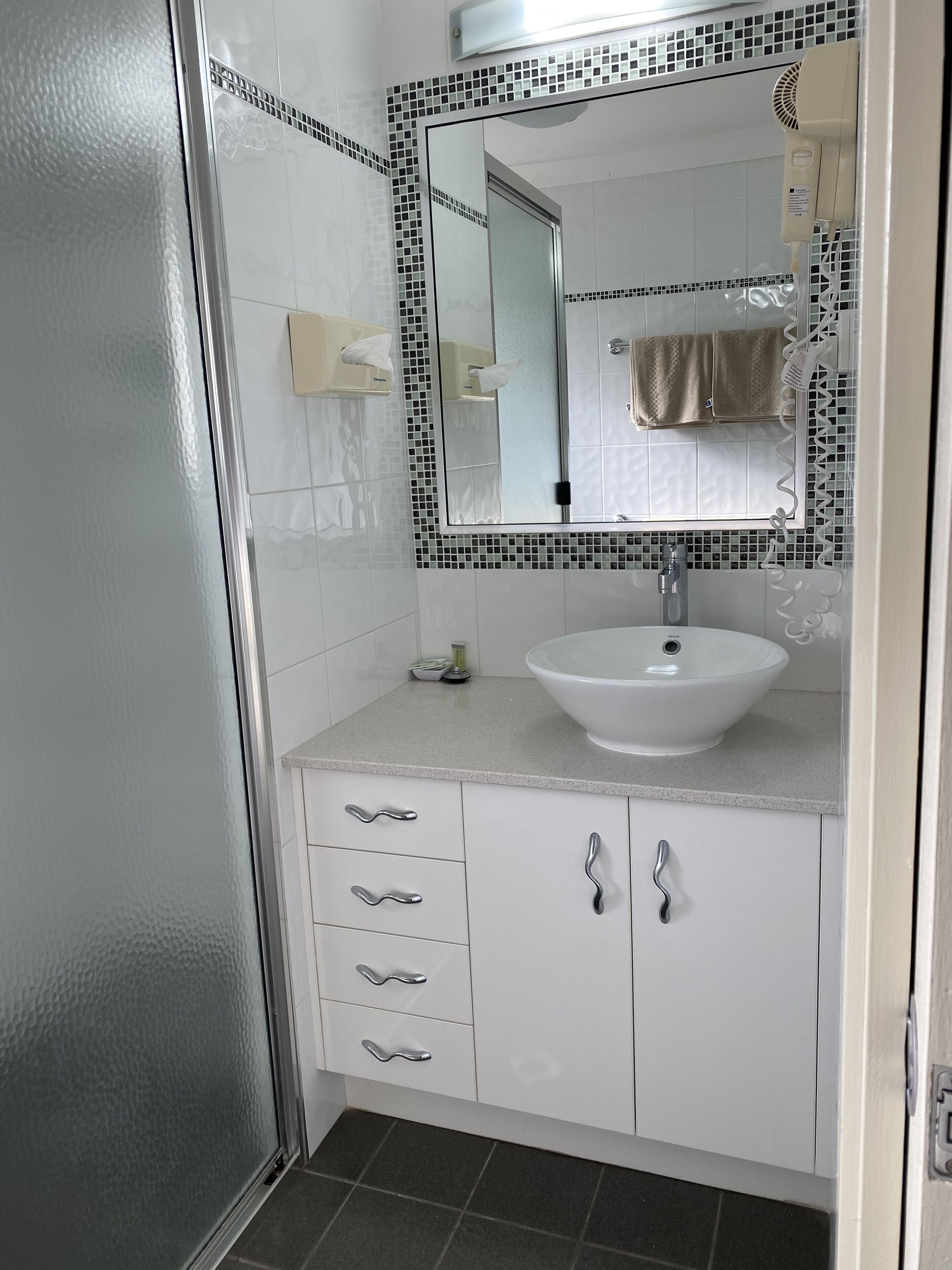 Casa de banho com lavatório branco, espelho e porta-toalhas.