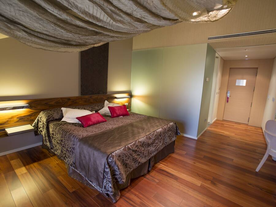 Quarto com cama de madeira, uma escrivaninha e uma cadeira.