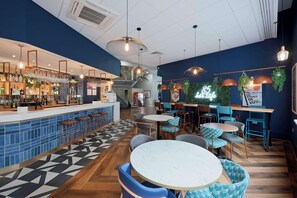 Interior moderno de café com balcão, assentos e escada.