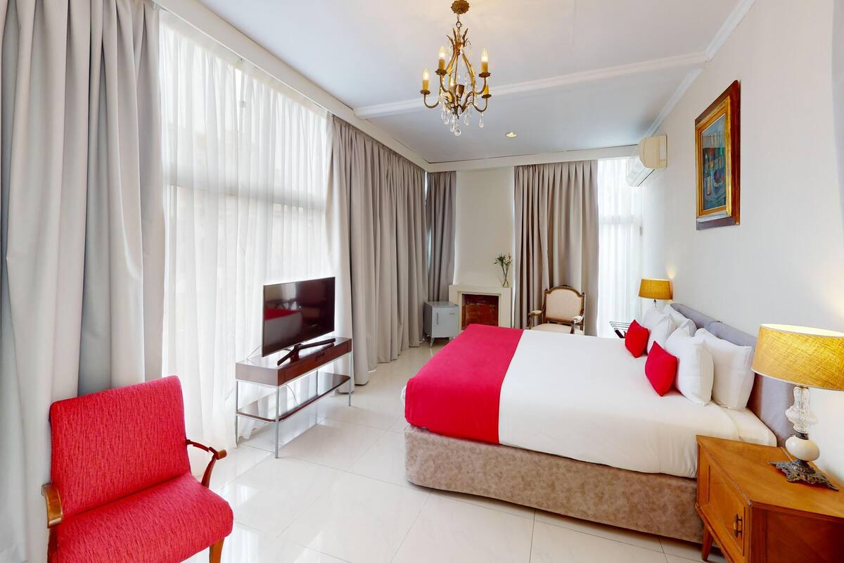 Quarto de hotel com uma cama grande, televisão, escrivaninha e uma cadeira.
