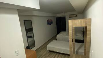 Quarto pequeno com cama beliche, escrivaninha e espelho.