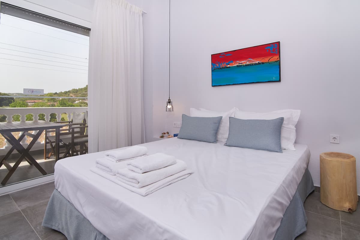 Quarto de hotel com cama, quadro, varanda e vista para a paisagem.