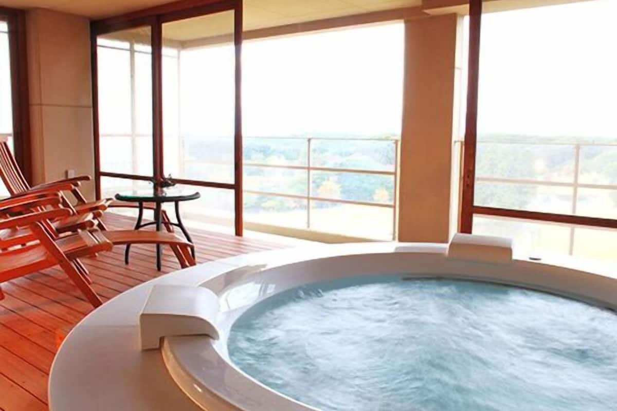Uma banheira de hidromassagem em um deck de madeira com vista para o oceano.