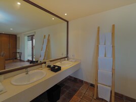 Casa de banho com duas pias, um espelho grande e uma cortina de chuveiro de bambu.