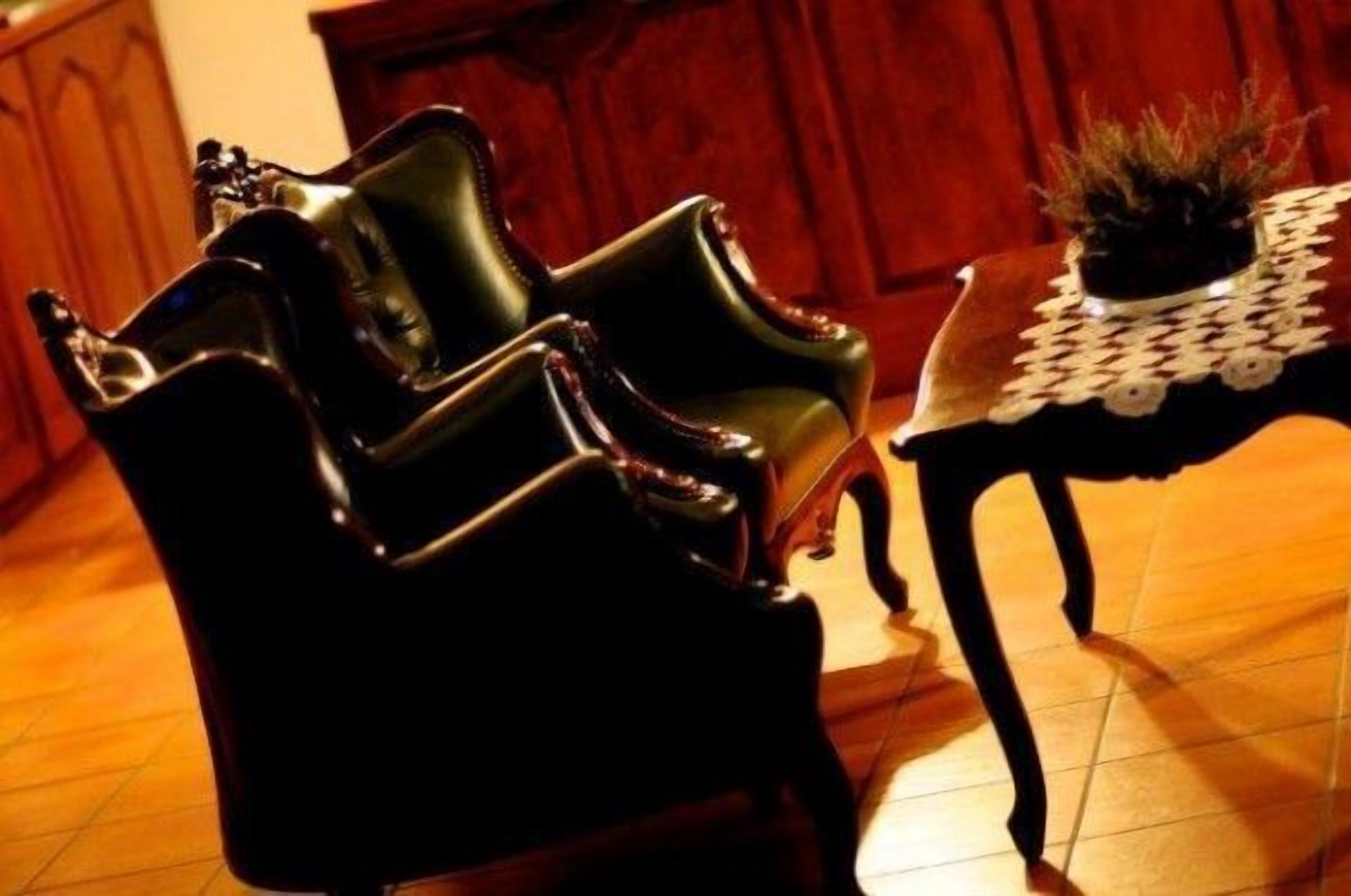 Um quarto com uma cadeira de madeira escura e uma mesa pequena com um objeto decorativo.