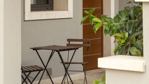 Um pátio com mesa, cadeiras, uma janela e uma porta.