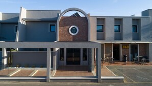 Um edifício moderno com uma janela circular central, um bar à direita e uma área de entrada coberta.