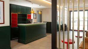 Uma área de recepção moderna com balcão verde, armários vermelhos e iluminação pendente.