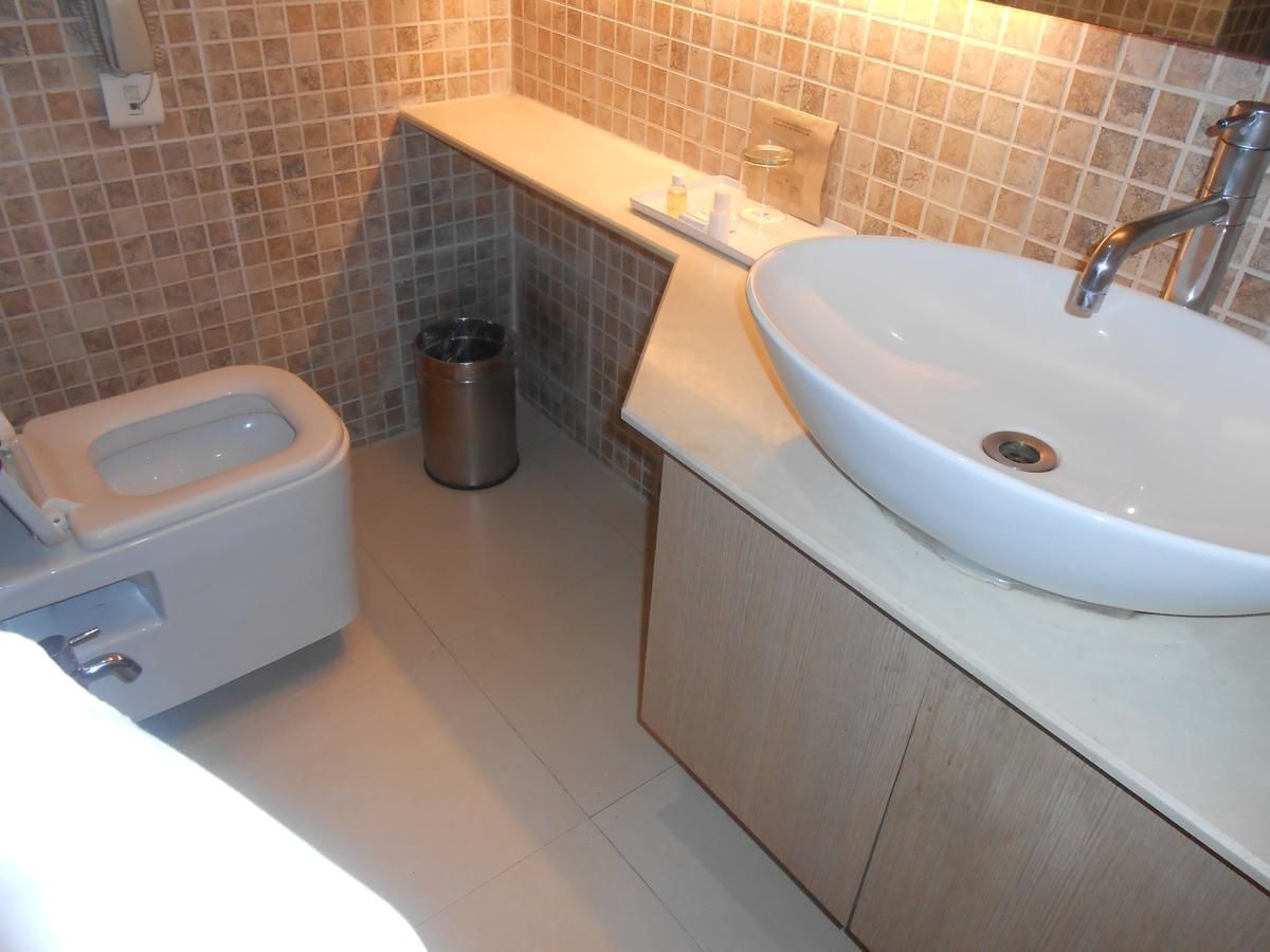 Uma casa de banho pequena com sanita, lavatório e um caixote do lixo.