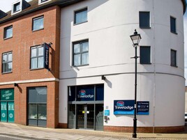 Um hotel Travelodge com fachada de tijolos e lateral branca.