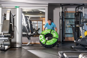 Academia com equipamentos de ginástica, um grande disco verde de exercício e uma esteira.