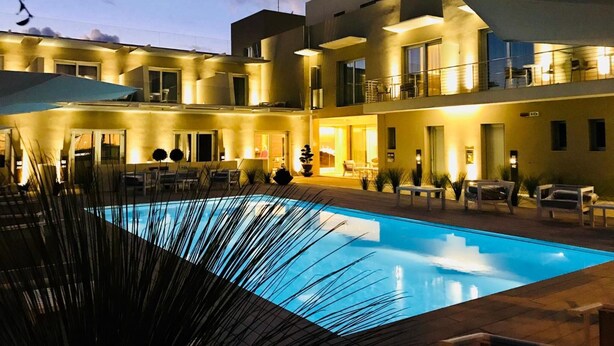 Um hotel moderno com piscina, várias varandas e áreas de estar ao ar livre.