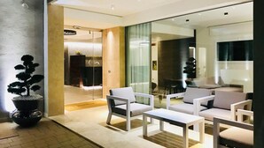 Um saguão de hotel moderno com área de estar, com sofás brancos e uma mesa de centro.