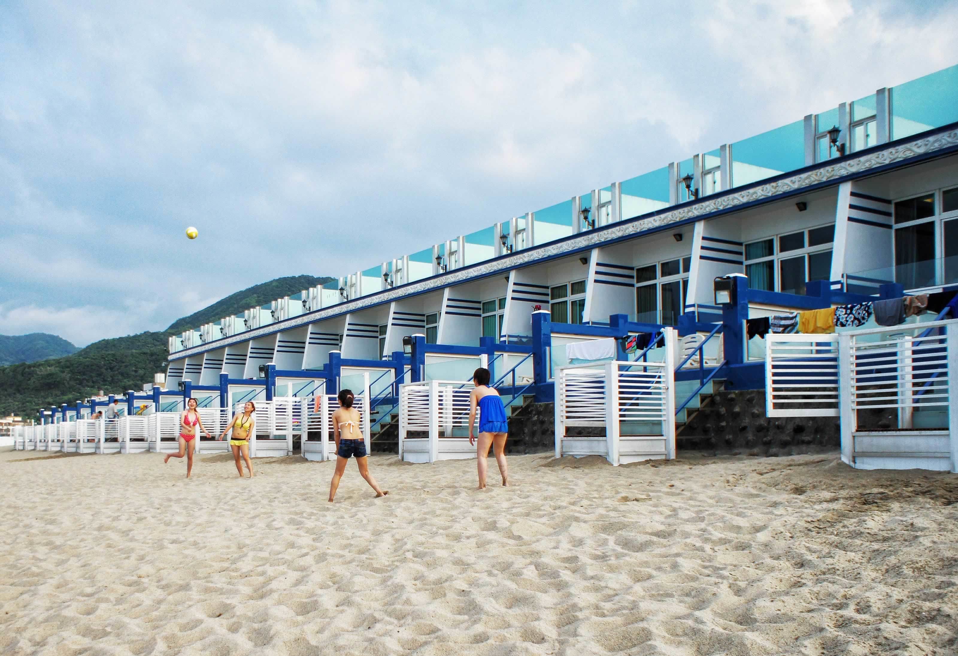 Um hotel à beira-mar com várias varandas e uma área de praia arenosa.
