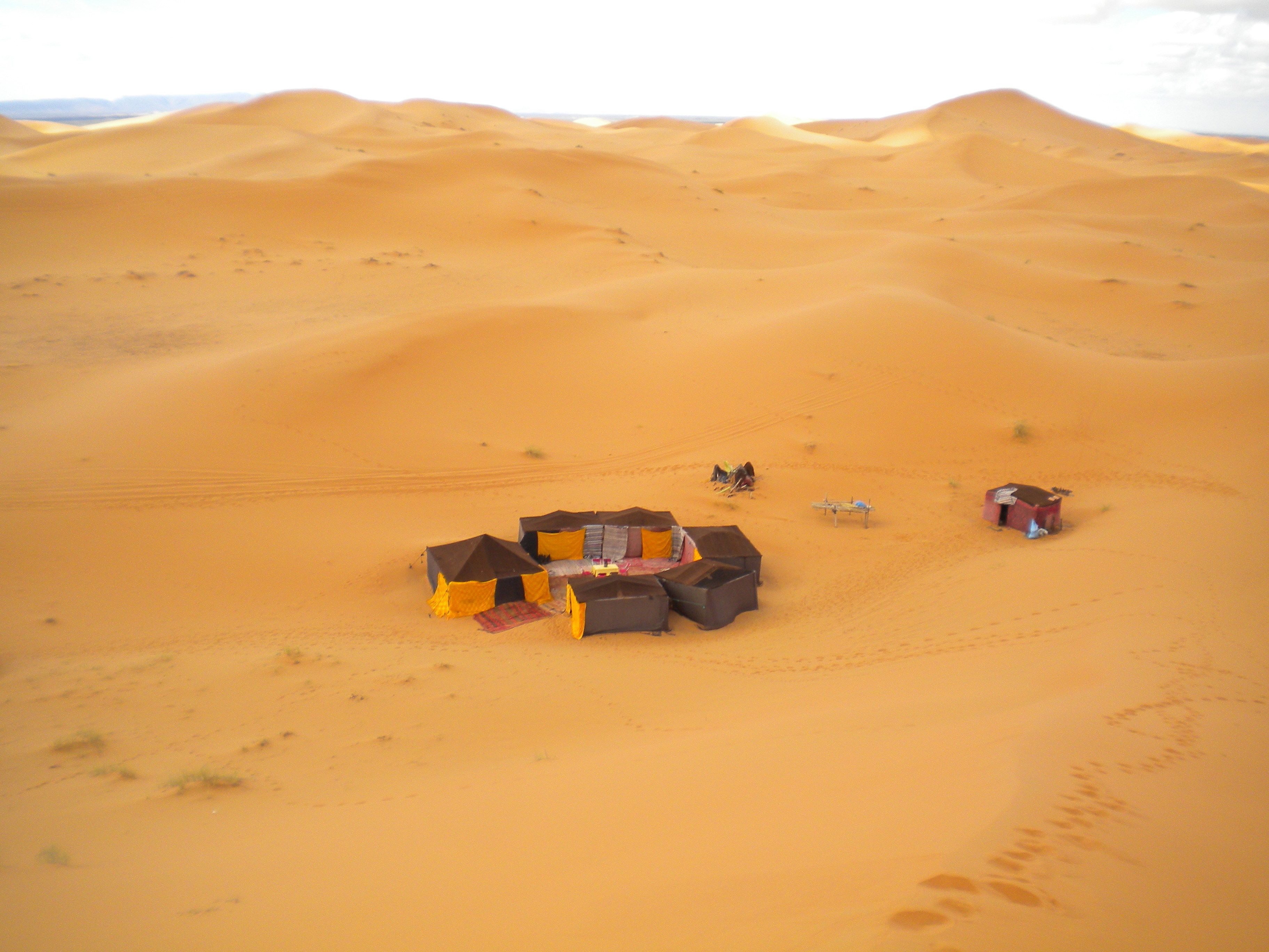 Cena de deserto com tendas e uma pequena construção.