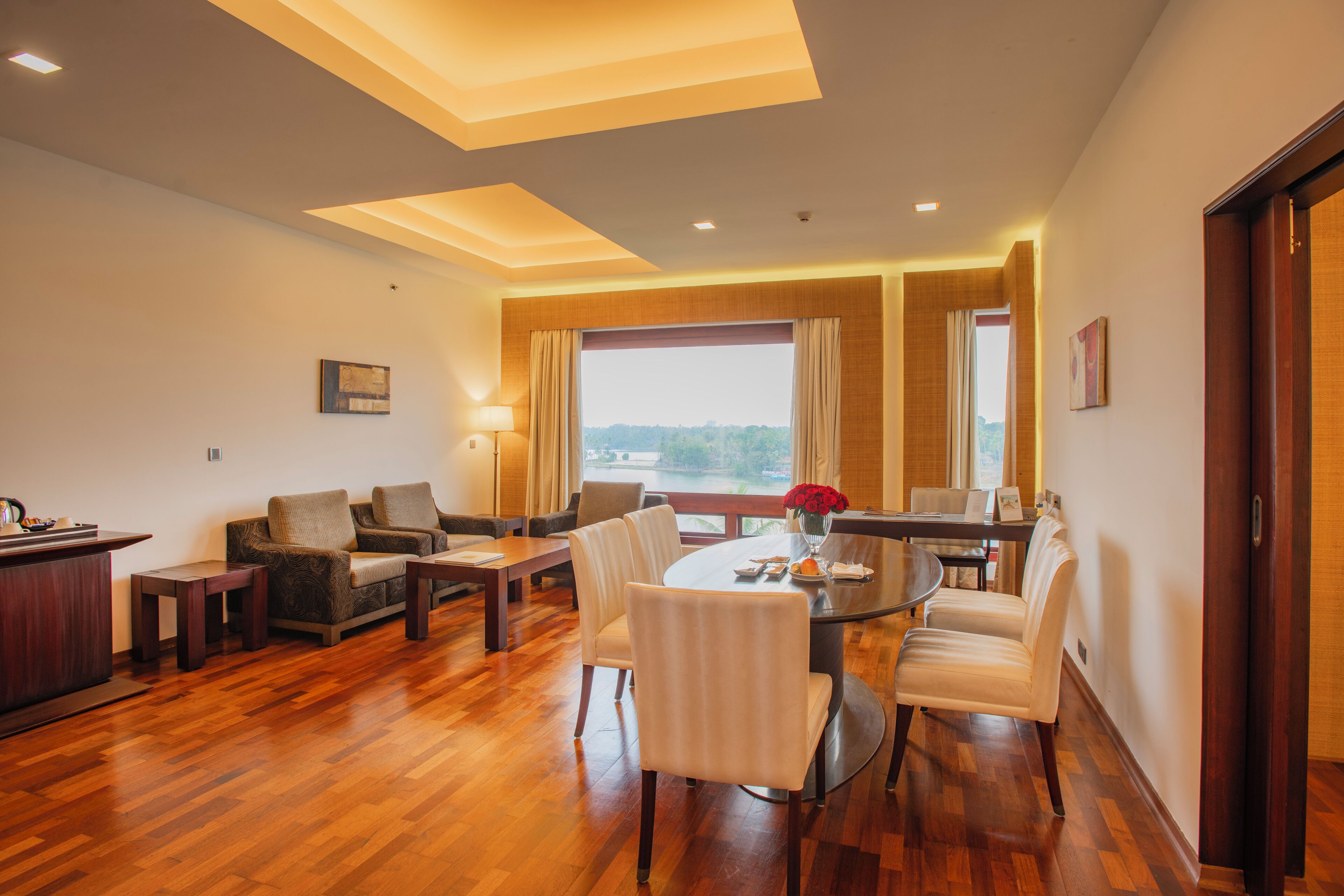 Ampla sala de estar com piso de madeira, uma mesa de jantar redonda com cadeiras, um sofá e uma mesa de centro.